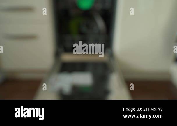 A hand shows a dishwasher tablet close-up against the background of an ...