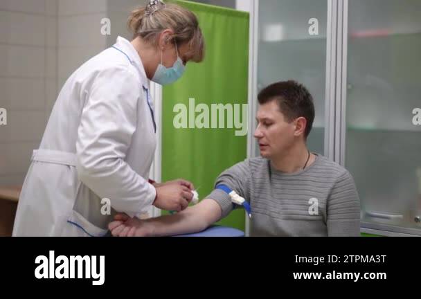 A female health worker in a clinic, makes a painful puncture in the ...