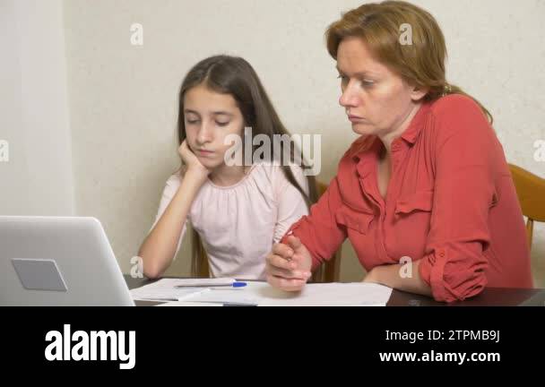 Mother and daughter working on a homework together on a laptop. online learning, online school ...