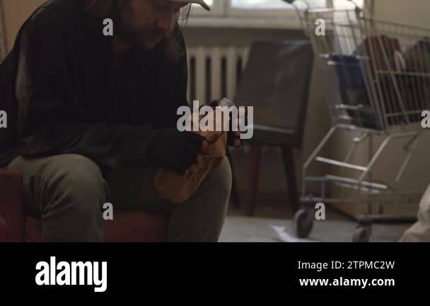 Boom shot. Homeless poor man sitting in a room of an abandoned building ...