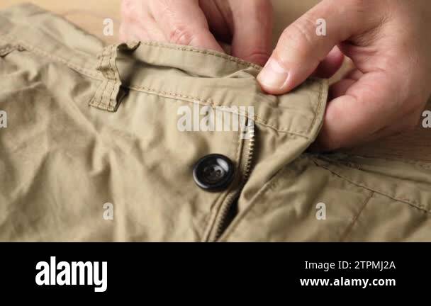 The button is sewn to the garment by hand using a needle and thread ...