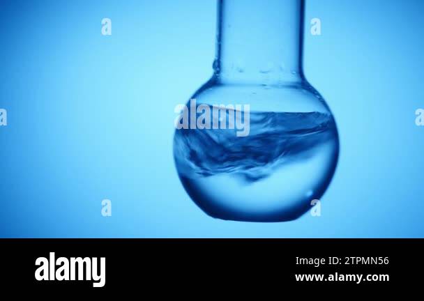 Shining water is twisted strongly in a round flask in a chemical ...