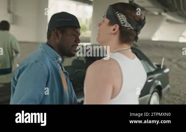 African American and Caucasian guy wearing rapper clothes pushing each ...