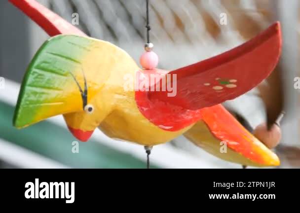 Wooden windmill kinetic sculpture of colorful bird develops in the wind ...