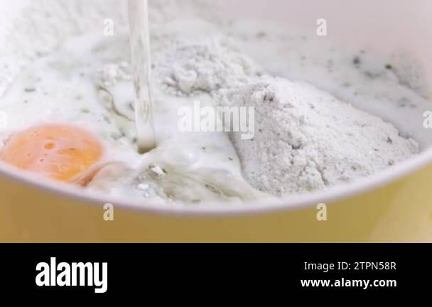 Water adding to cereal flour with egg for homemade bread preparation ...