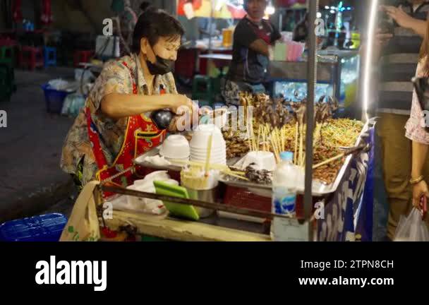 A woman sells bugs in night market at Chinatown. Fried insects and ...