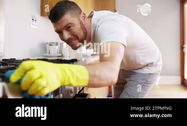 Man, stove cleaning and scrub from washing and kitchen with rubber ...