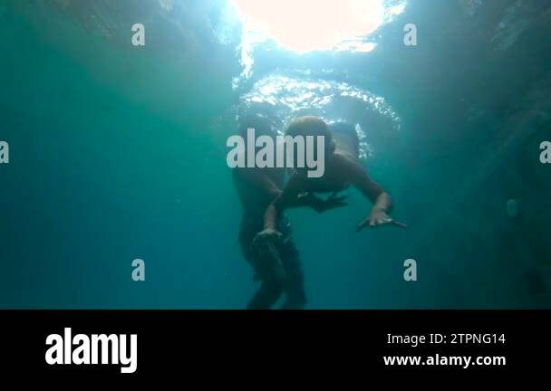 ultrahd slowmotion underwater shot of a father teaching his son how to ...