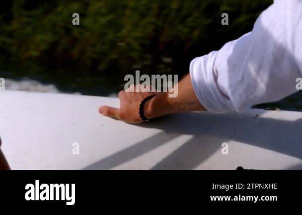 A mans hand rests on the side of a speedboat yacht. sailing fast on the ...