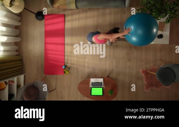 Top view capturing a young woman doing exercises using an exercise ball ...