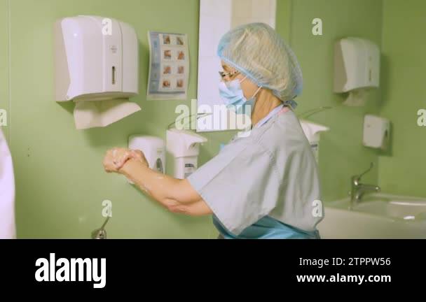 Before the operation, a senior female surgeon washes her hands ...