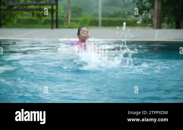 Little girl plays in the outdoor swimming pool of tropical resort ...