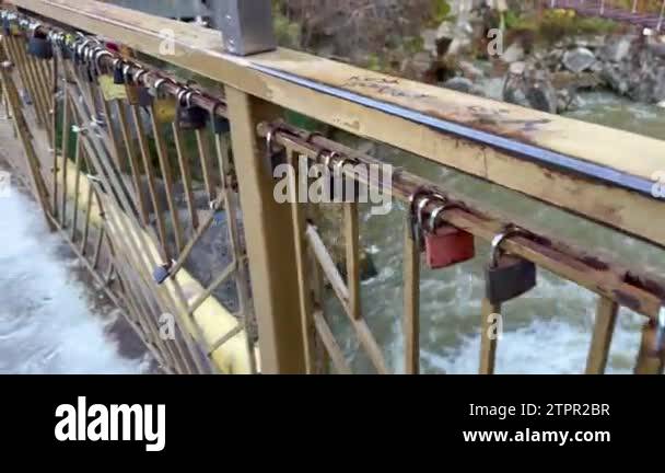 Love padlocks on a footbridge across the river. Many locks are attached ...