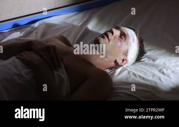 man with head injuries lying on the bed. bandaged head. bruise on his ...
