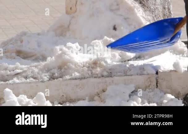 shoveling manually white snow from the street with shovel, clearing ...