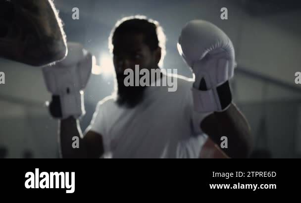 Dramatic fighter wearing boxing gloves standing inside ring facing ...