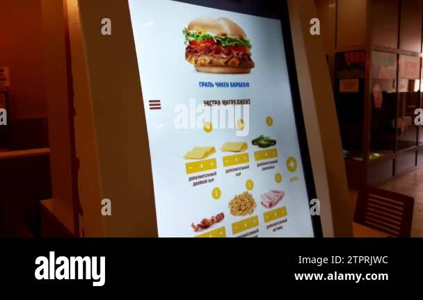 Woman uses a touchscreen for ordering hamburgers in fast food ...