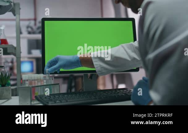 Unrecognizable scientist typing green screen computer holding test tube ...