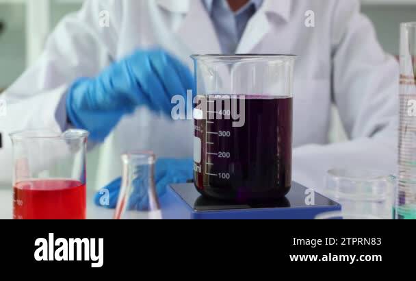 Chemical laboratory glass flask with clear liquid is mixed with ...