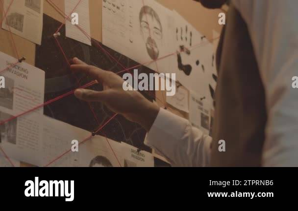 Low angle shot of Black male detective attaching old newspaper clipping ...