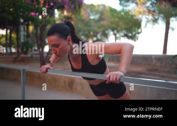 Woman doing push-ups in park. Female athlete performing incline push ...