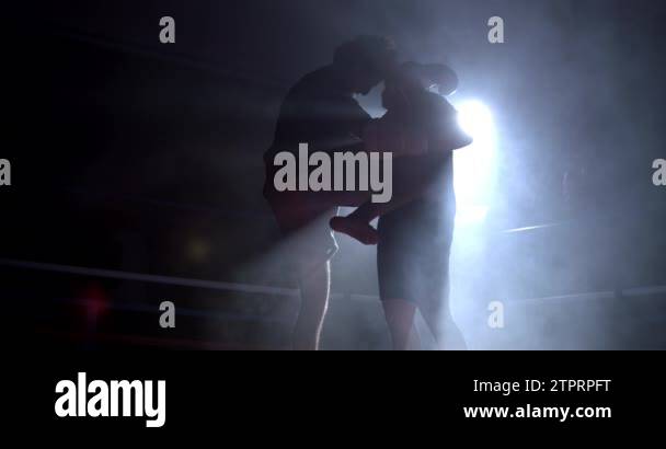 Two fighters inside ring with dramatic backlight. Young man blowing a ...