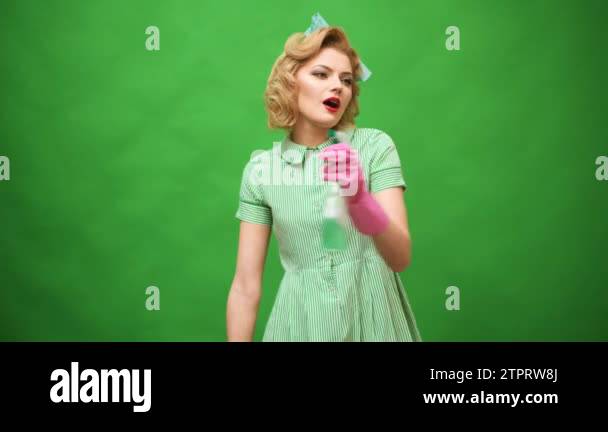 Pin up woman in gloves smiling and wiping dust using a spray and a ...