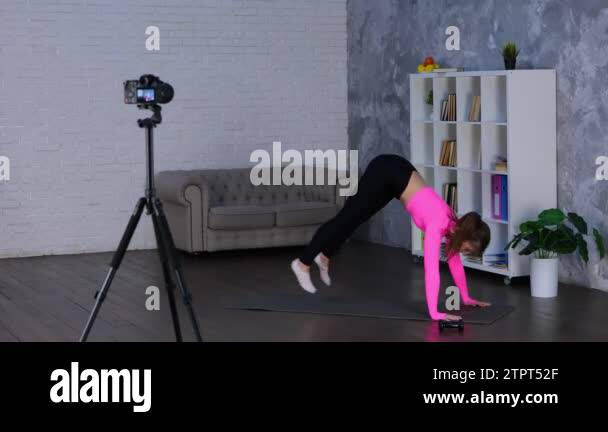 Sporty young lady exercising in the living room at home while doing ...