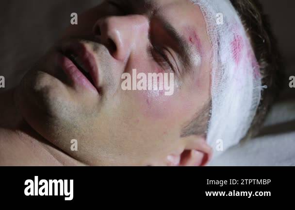 man with head injuries lying on the bed. bandaged head. bruise on his ...
