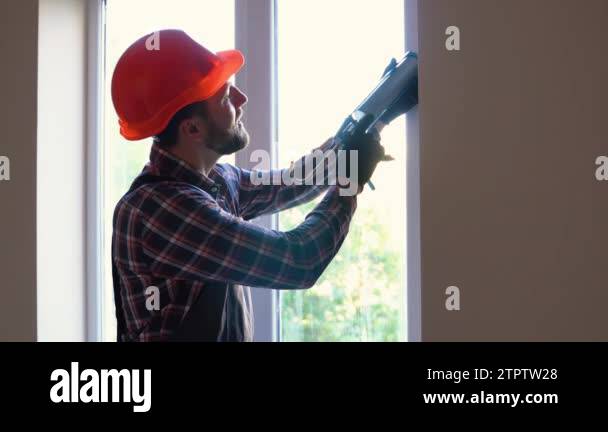 Handyman is applying polyurethane foam to fill gap between sash and ...