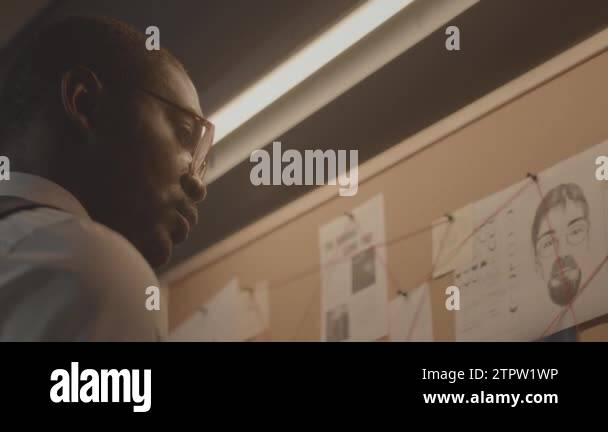 Low angle of professional Black male FBI agent inspecting suspects ...