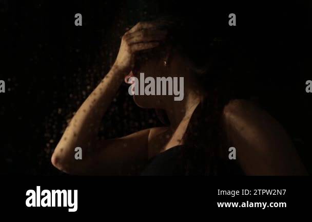 young sad woman behind the window with drops on it. lonely girl ...