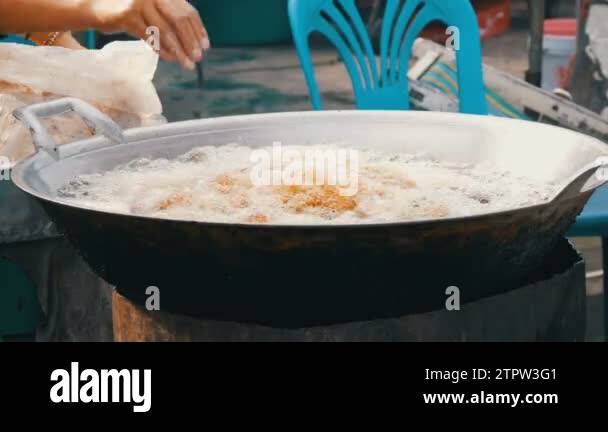 Street food in Thailand and Asia. Large boiling vat in which woman hand ...