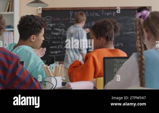 Waist up of multiracial teenage classmates chatting during programming ...