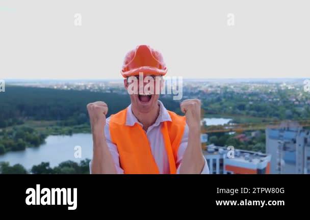 Happy male employee in helmet screaming while celebrating success on ...