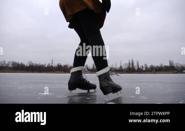 Legs of woman shod in figure skates sliding on ice at nature. Female ...