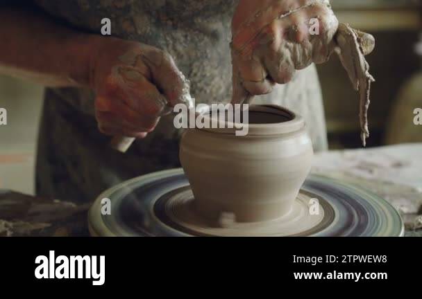 Close-up shot of half-finished ceramic pot spinning on throwing wheel ...