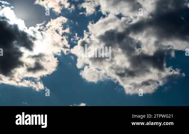Timelapse of cumulus clouds moving in the blue sky against the sun ...