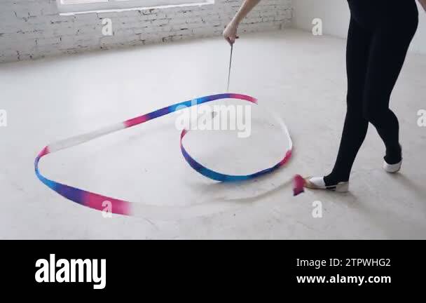 Close up shot of teenage gymnastics legs in black spinning the colored ...