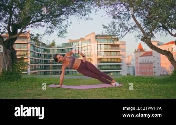 Fitness woman training body core at rubber mat outdoors. Motivated sportswoman making plank on ...