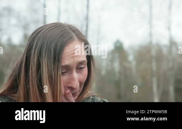 Young brown-haired woman crying and Smoking a cigarette near the hood ...