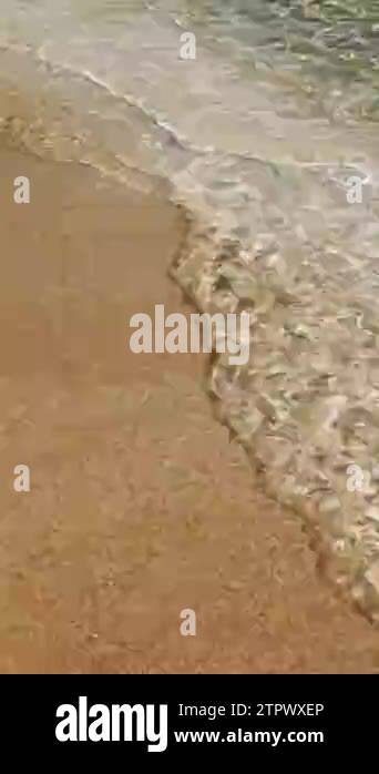 Sea waves roll onto the beach, a peaceful daytime scene. Gentle waves ...