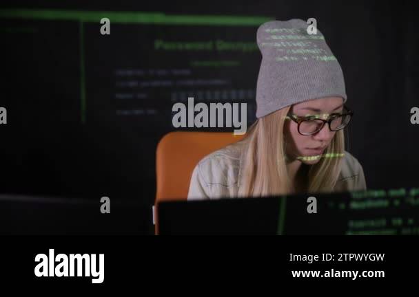 Female hacker working at the computer in dark at night. Binary code ...