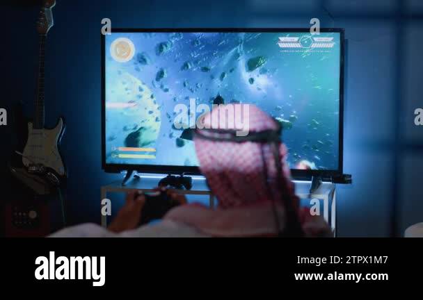 Middle Eastern gamer plays classic arcade action videogame, flying ...