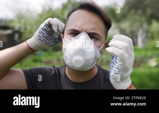 Man in working gloves puts on the resperator in slow motion outdoors ...