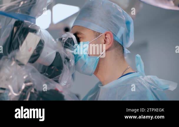 Neurosurgery process. Surgeon in medical hat and mask is looking into ...