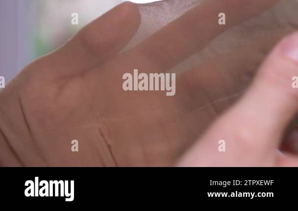 close-up. Female hands test the integrity of kapron stockings. a torn ...