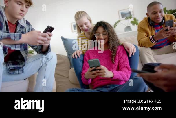 Happy diverse group of teenage friends using smartphones and laughing ...