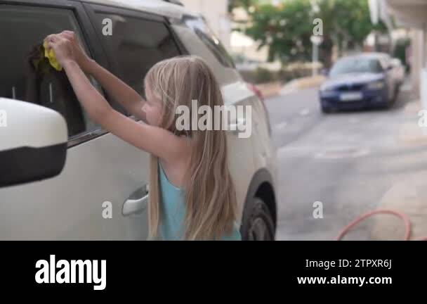 Beautiful little girl washing the window of a car in the yard Stock ...