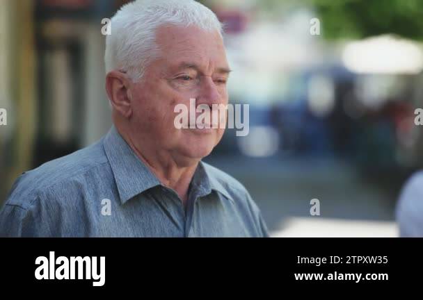 Brave grey-headed man stands in a green street and thinks on a sunny ...